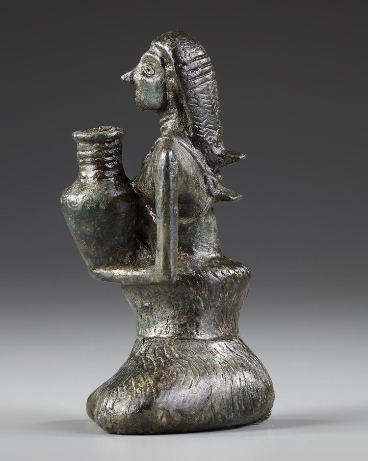 A BACTRIAN STATUETTE OF A SITTING FEMALE HOLDING A JAR, CIRCA 2700 B.C.