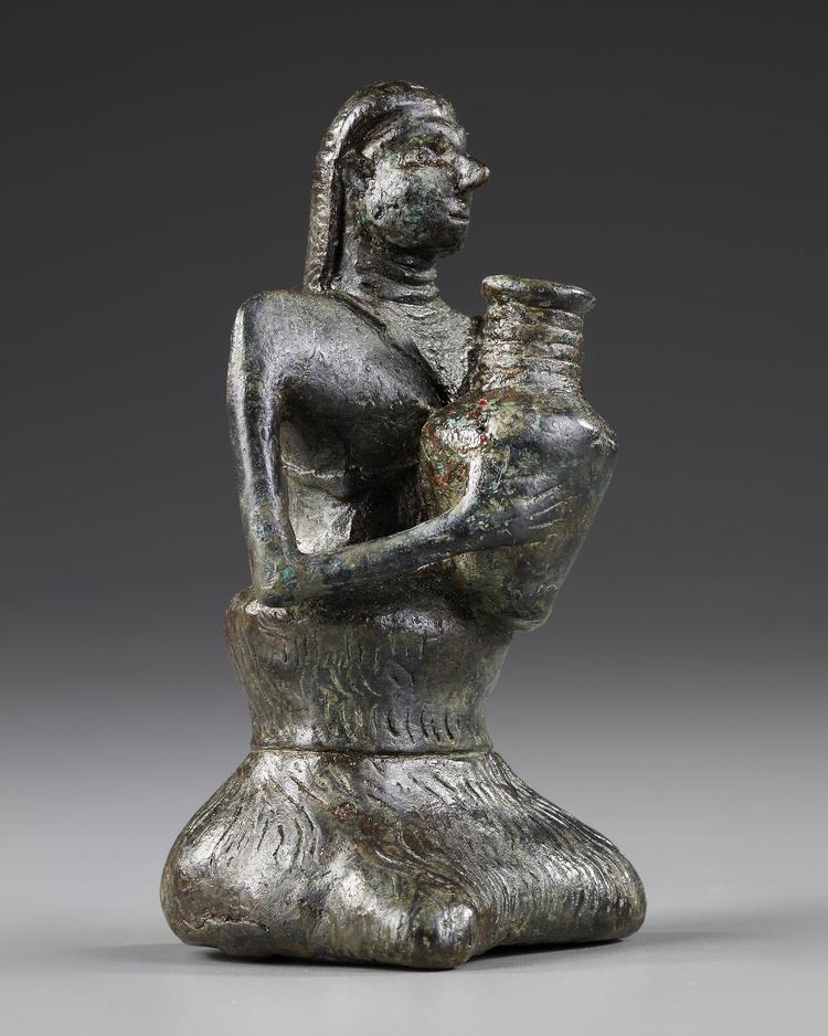 A BACTRIAN STATUETTE OF A SITTING FEMALE HOLDING A JAR, CIRCA 2700 B.C.