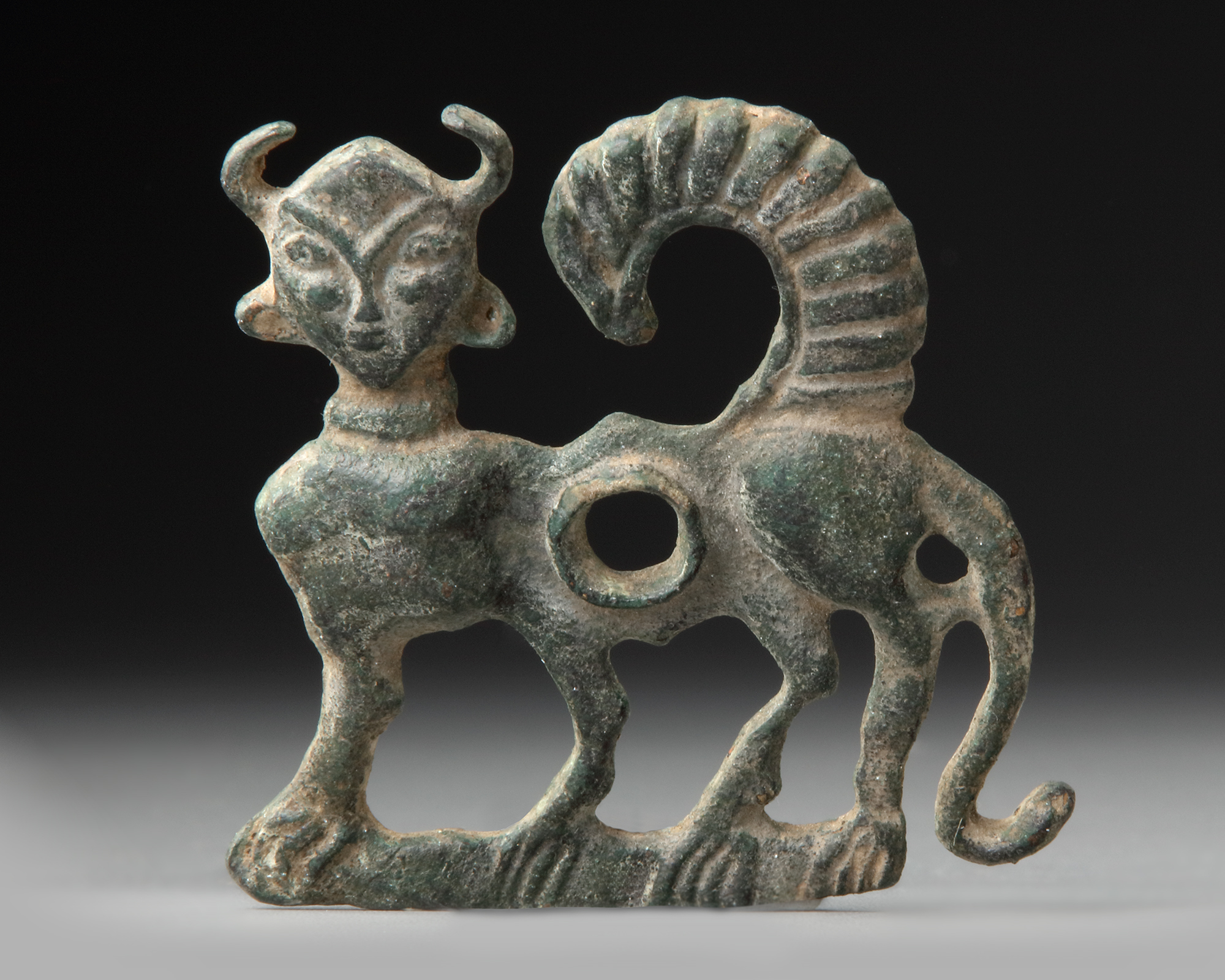 A HORSE BIT IN THE FORM OF A HUMAN-HEADED WINGED BULL, LURISTAN, CIRCA ...