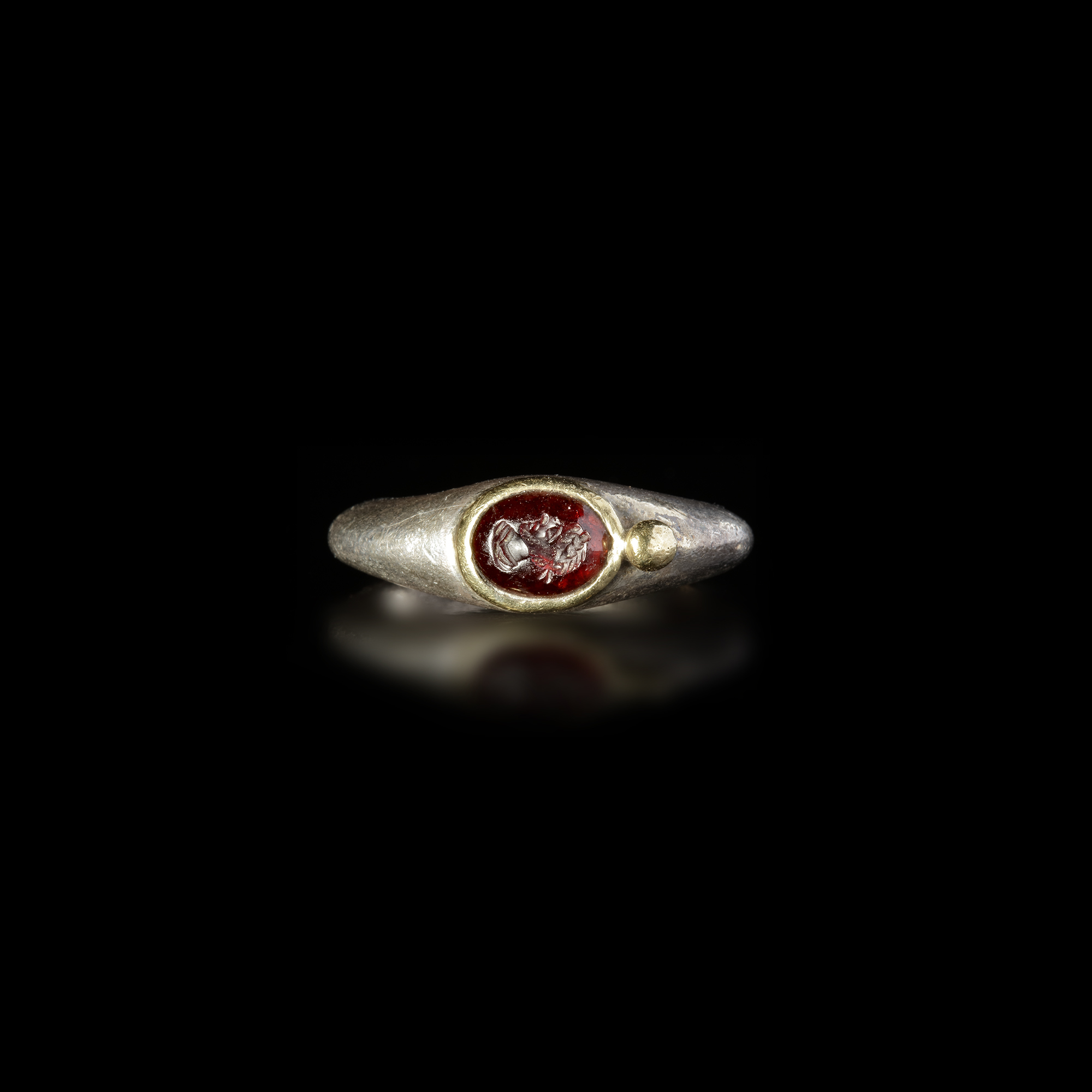 A SILVER ROMAN RING WITH A GOLD MOUNT HOLDING A GARNET INTAGLIO, 3RD ...
