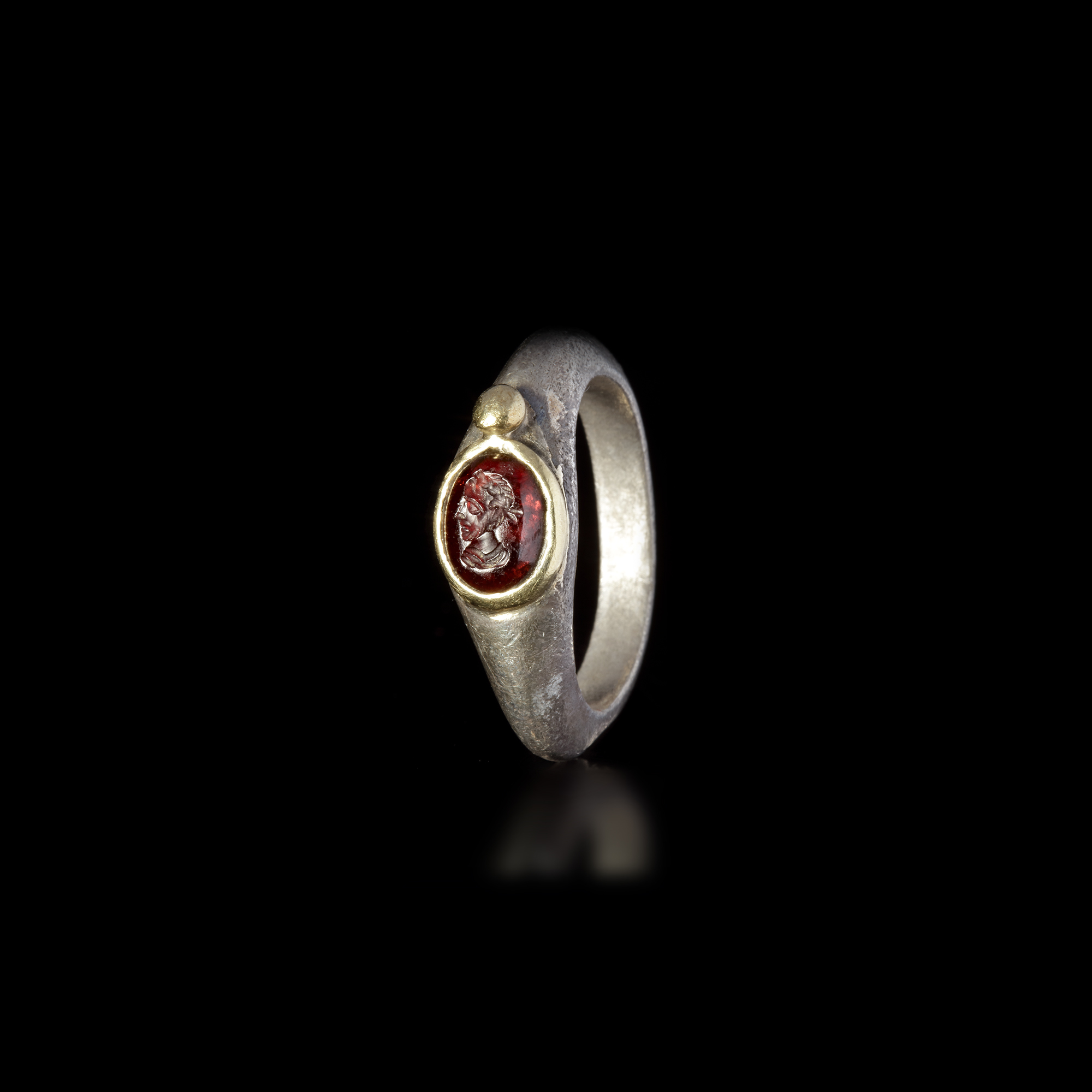 A SILVER ROMAN RING WITH A GOLD MOUNT HOLDING A GARNET INTAGLIO, 3RD ...